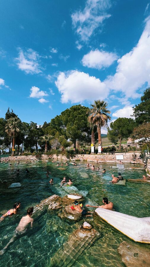 Visitors enjoying the natural thermal pools at Pamukkale with travertine formations