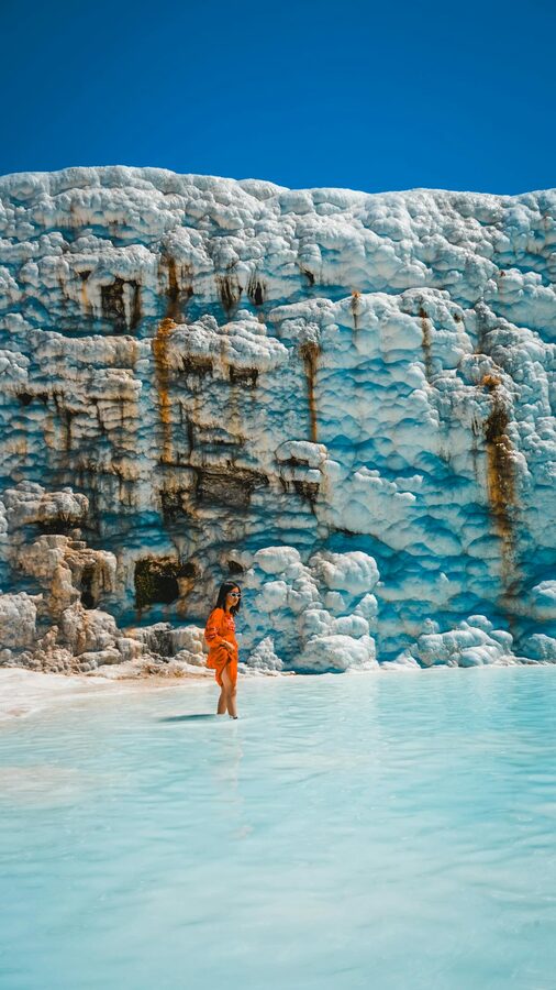Person walking through turquoise travertine pools at Pamukkale Denizli Turkey