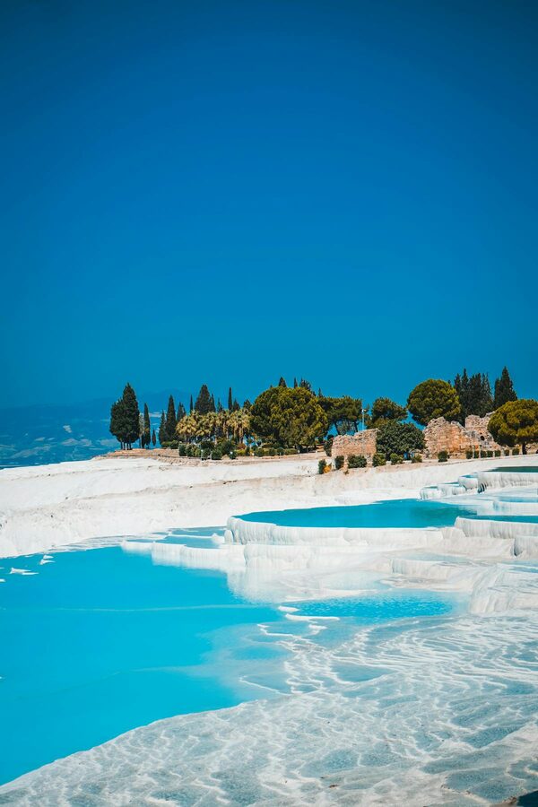 Bright white travertine terraces with blue thermal pools at Pamukkale Turkey