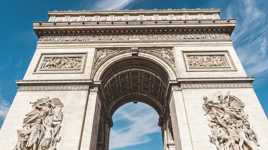 Low-angle view of the Arc de Triomphe against a clear blue sky