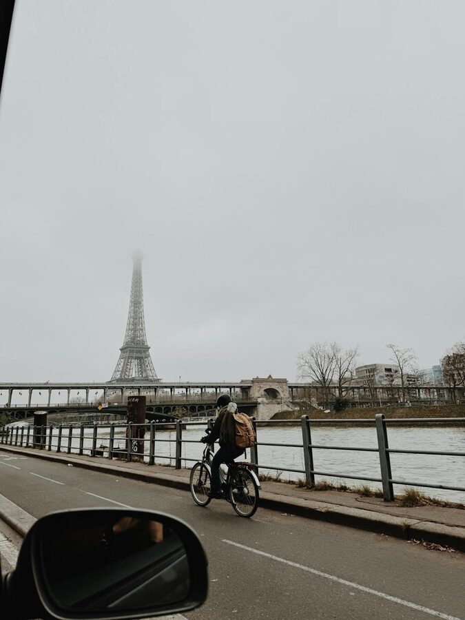 Cyclist riding along the Seine River near the Eiffel Tower on a misty morning in Paris