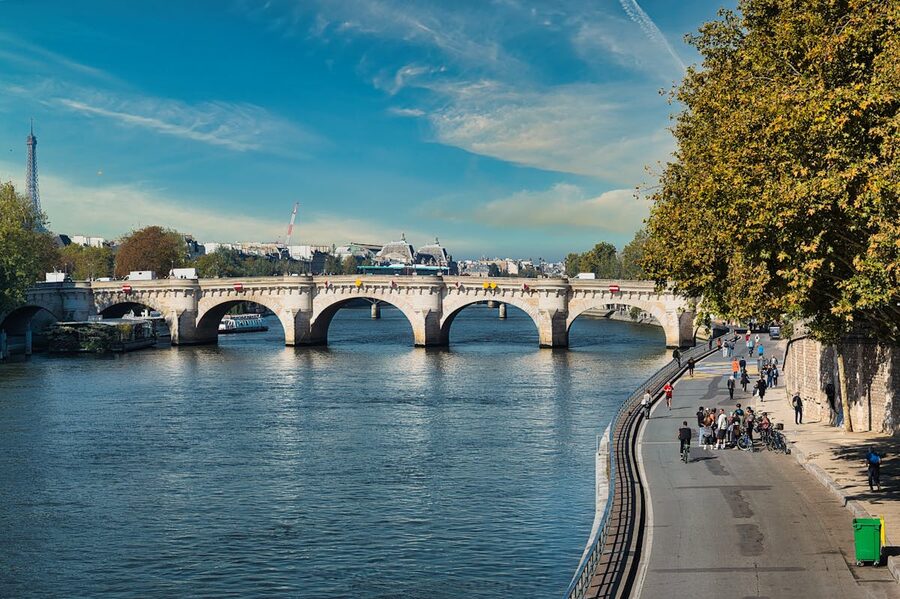 Pont Neuf bridge spanning the Seine River with cyclists and pedestrians crossing on a sunny day