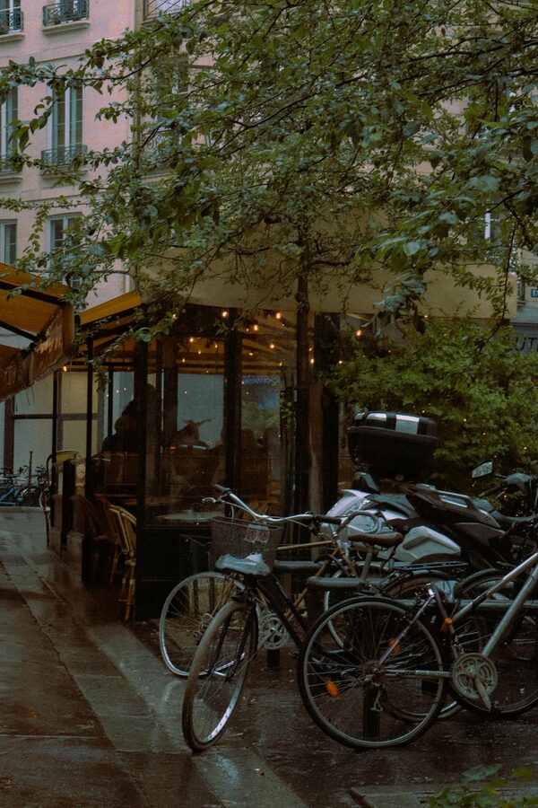 Bicycles parked by a Parisian café on a rainy day with wet cobblestones