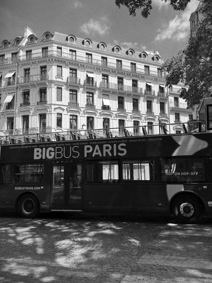 Big Bus Paris tour bus under trees on a Parisian street