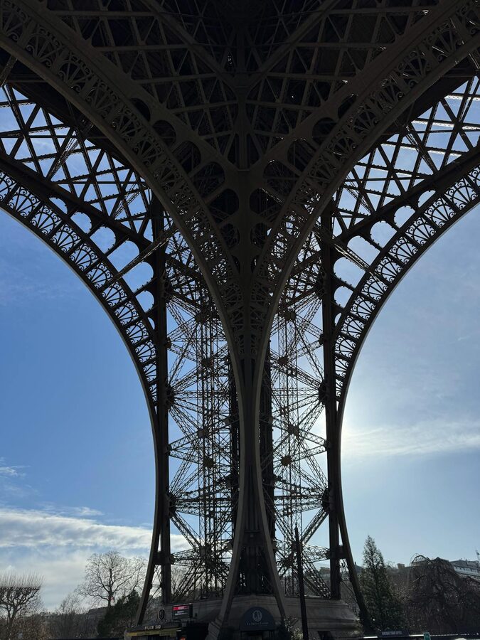 Looking up at the Eiffel Tower's iron lattice from directly below