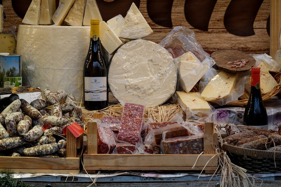 Assorted cheeses, sausages, and wine bottles in a rustic market setting