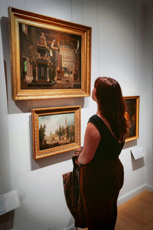 Woman in a Paris gallery studying classical artwork in ornate frames