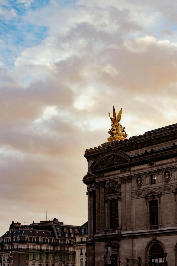 Golden statues on the exterior of the Palais Garnier against a blue sky