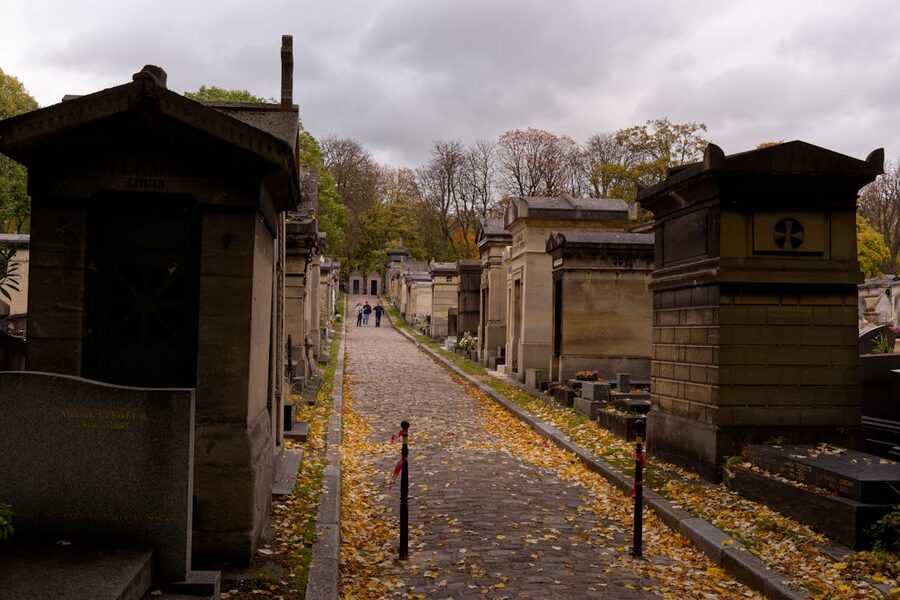 Historic cemetery path lined with old tombs on an overcast autumn day