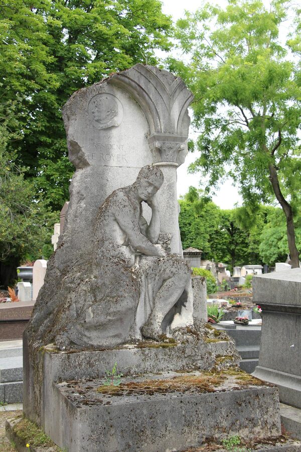 Elegant stone sculpture at Père Lachaise surrounded by greenery