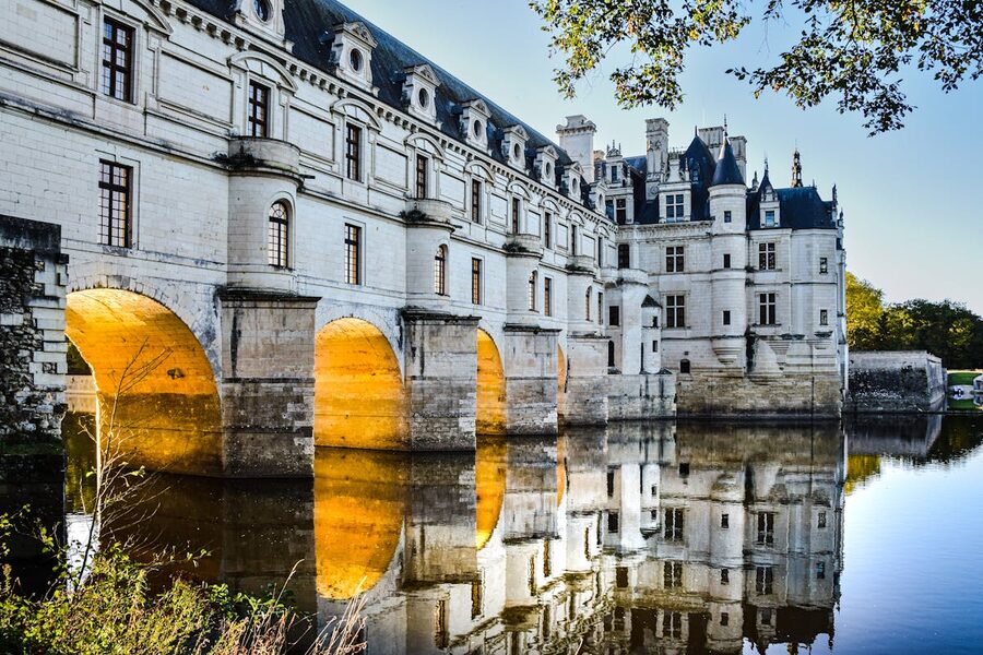 Château de Chenonceau illuminated at dusk with arches reflecting in the River Cher