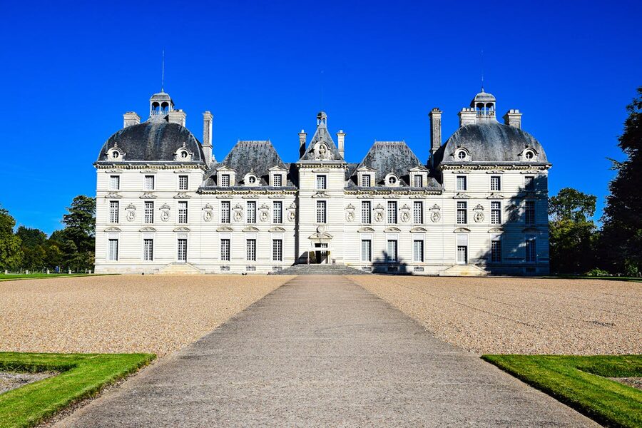 Classical white facade of Château de Cheverny with symmetrical wings and manicured lawn