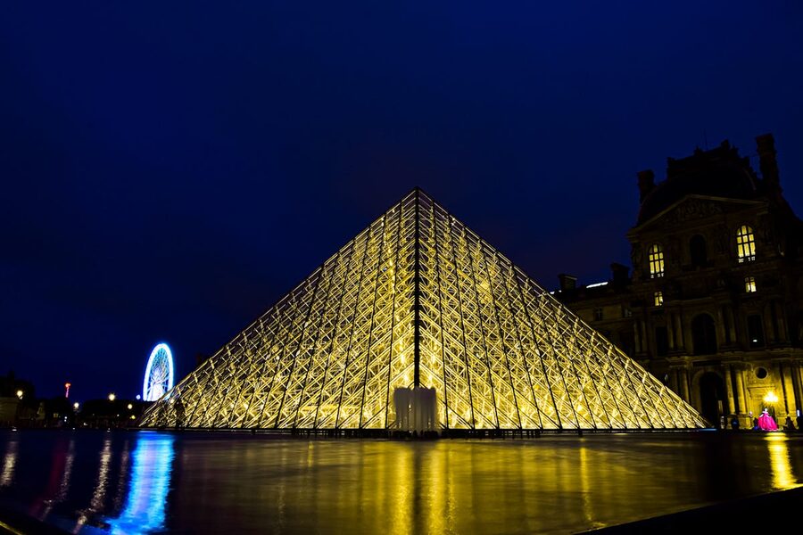 Louvre Pyramid illuminated at night with golden lighting