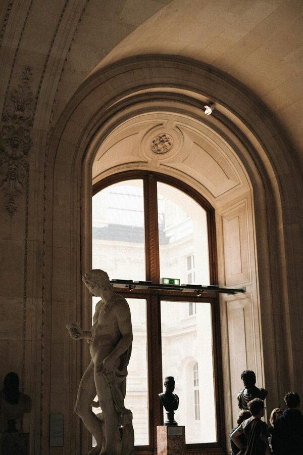 Sculptures and visitors in a gallery inside the Louvre Museum Paris