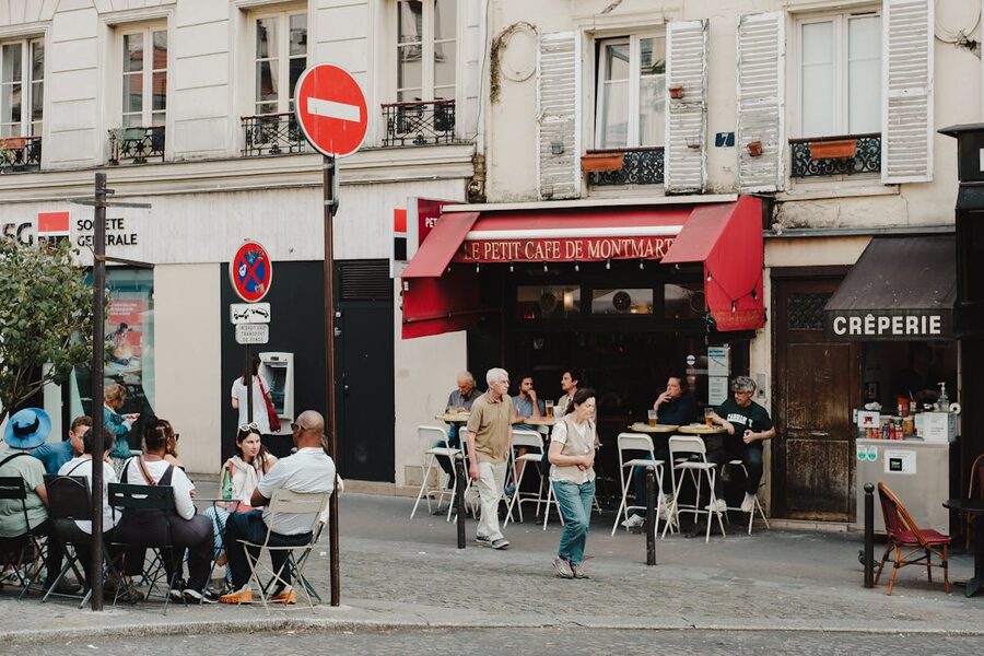 Outdoor café terrace at Le Petit Café de Montmartre with diners and flowering plants