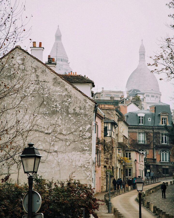 Montmartre street with Sacré-Coeur Basilica in the background and Parisian buildings lining the road