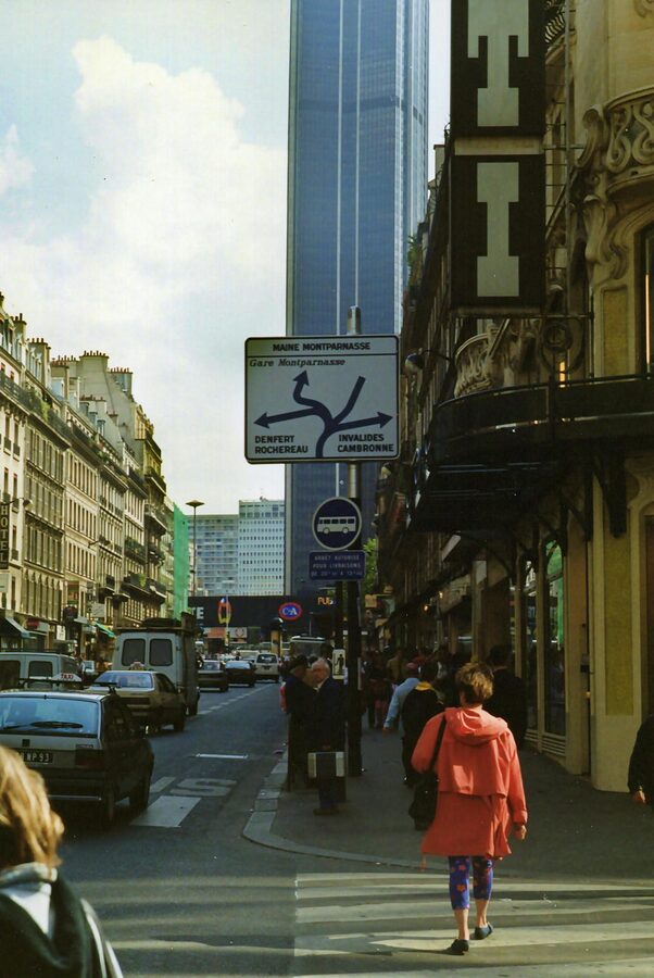 Paris street view looking toward Montparnasse Tower with classic Haussmann buildings in the foreground