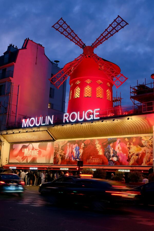 The Moulin Rouge area at night with neon lights and Parisian street life
