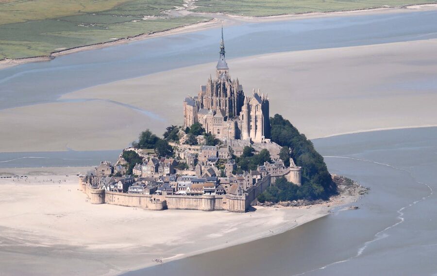 Aerial view of Mont Saint-Michel surrounded by tidal mudflats and water