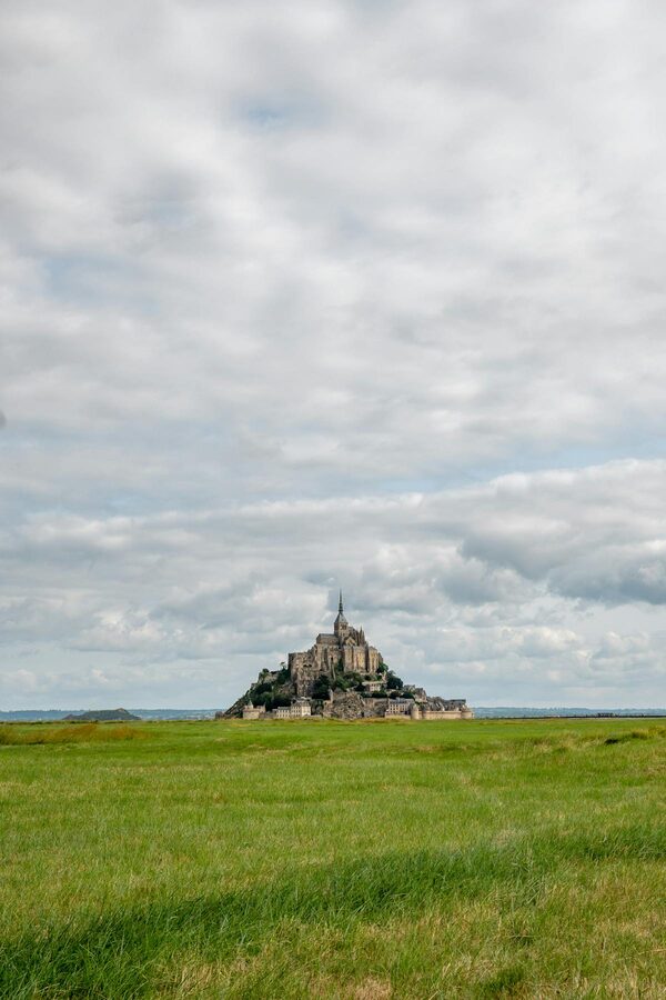 Mont Saint-Michel in misty atmospheric conditions rising from calm water