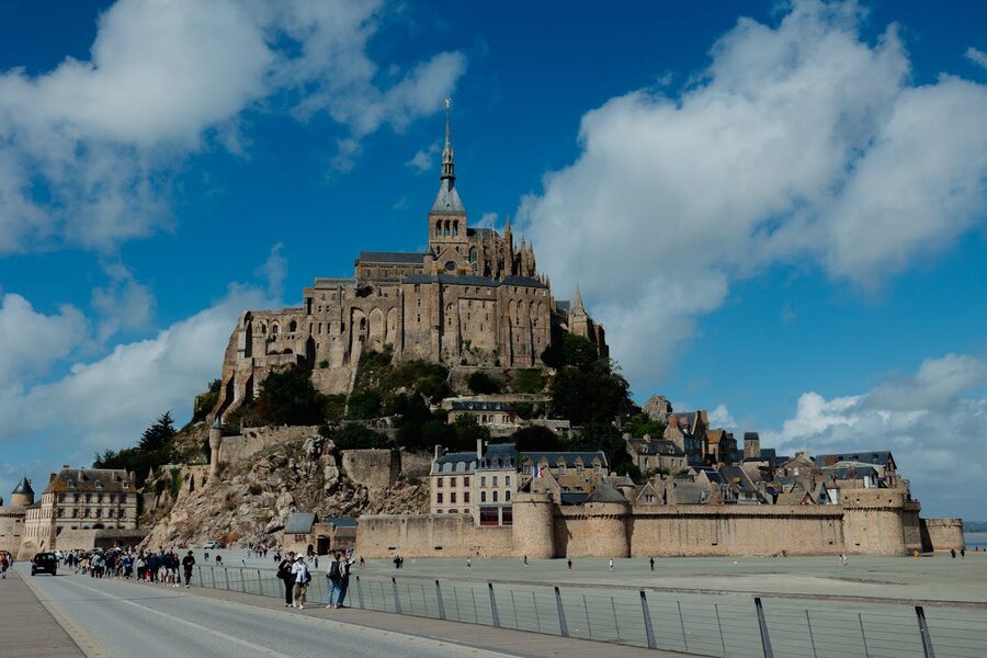 Mont Saint-Michel on a bright sunny day with visitors on the causeway