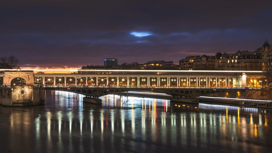 Nighttime view of a Paris bridge with reflections on the Seine