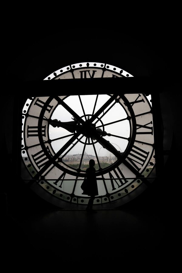 Silhouette of a visitor standing by the Musée d'Orsay clock