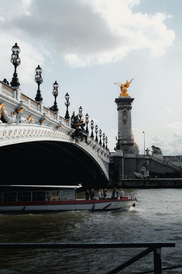 A boat passing under the ornate Pont Alexandre III bridge on the Seine