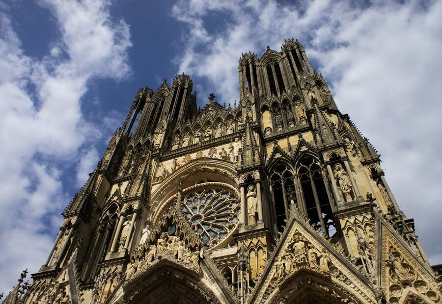 Reims Cathedral facade showing Gothic architecture and detailed stone carvings against a blue sky
