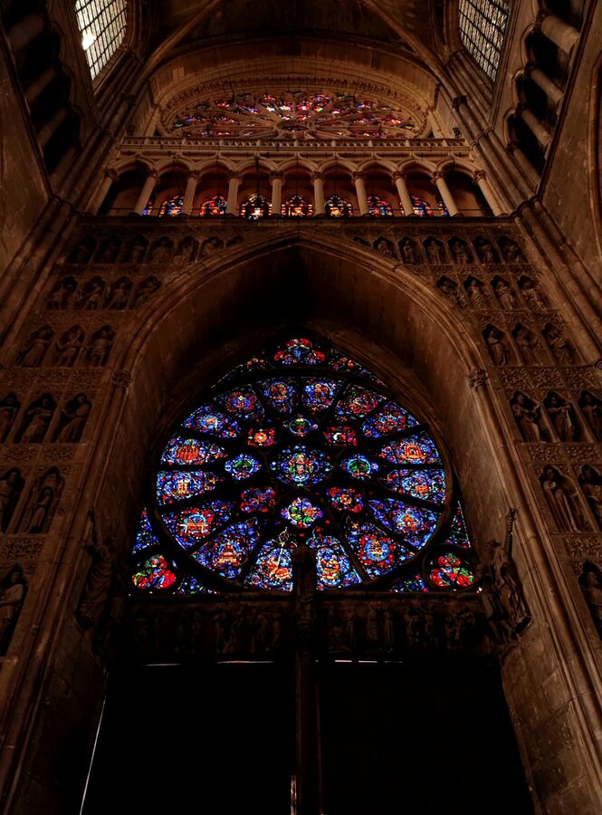 Rose window with detailed stained glass patterns inside Reims Cathedral