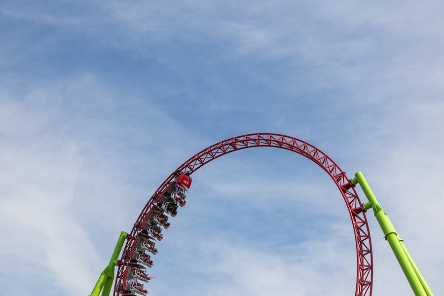 A roller coaster performing a loop against a clear blue sky