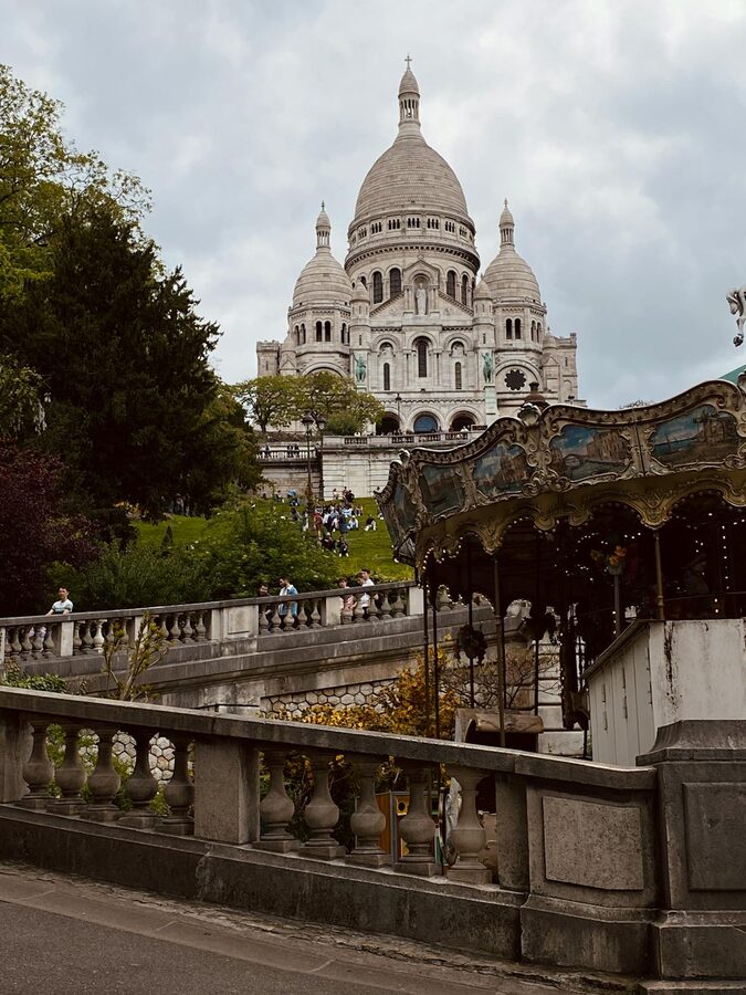 Sacré-Coeur Basilica overlooking a classic Parisian carousel at the base of the hill