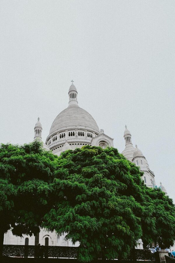 Sacré-Coeur Basilica domes surrounded by green trees against a clear sky
