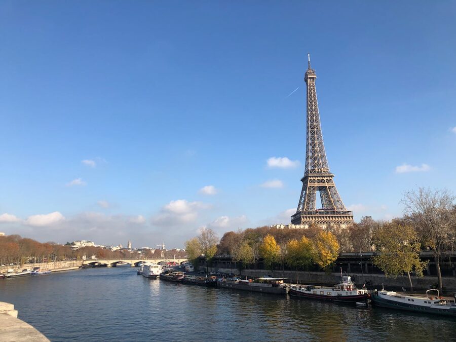 Boats on the Seine River near a bridge with the Eiffel Tower in the background