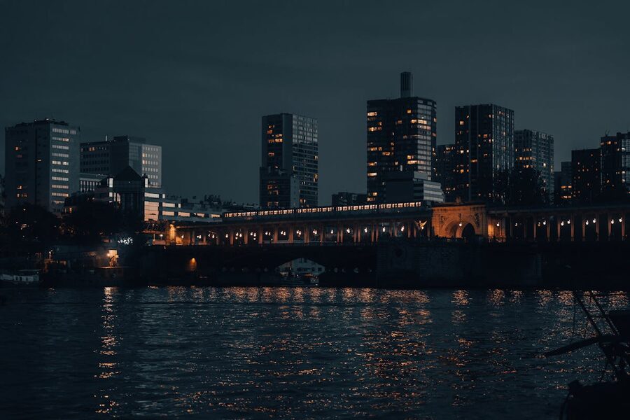 Paris skyline at night with buildings illuminated and reflecting in the river
