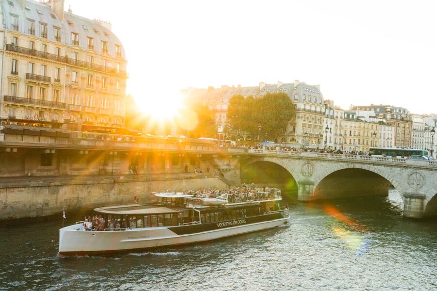 River cruise boat on the Seine during golden hour with Paris buildings in warm light