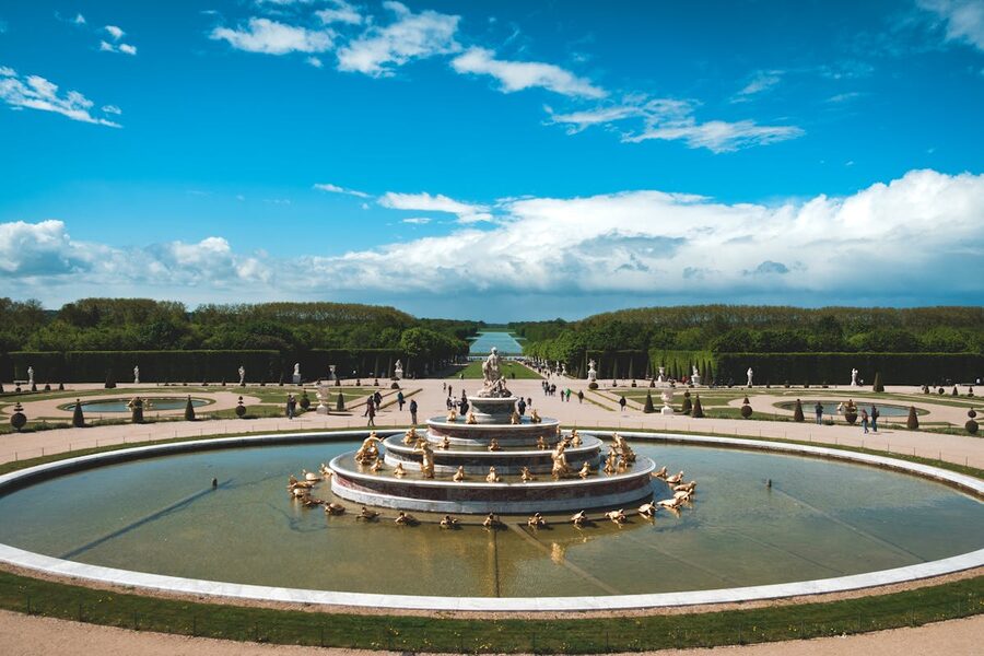 A fountain in the Gardens of Versailles with statues on a sunny day