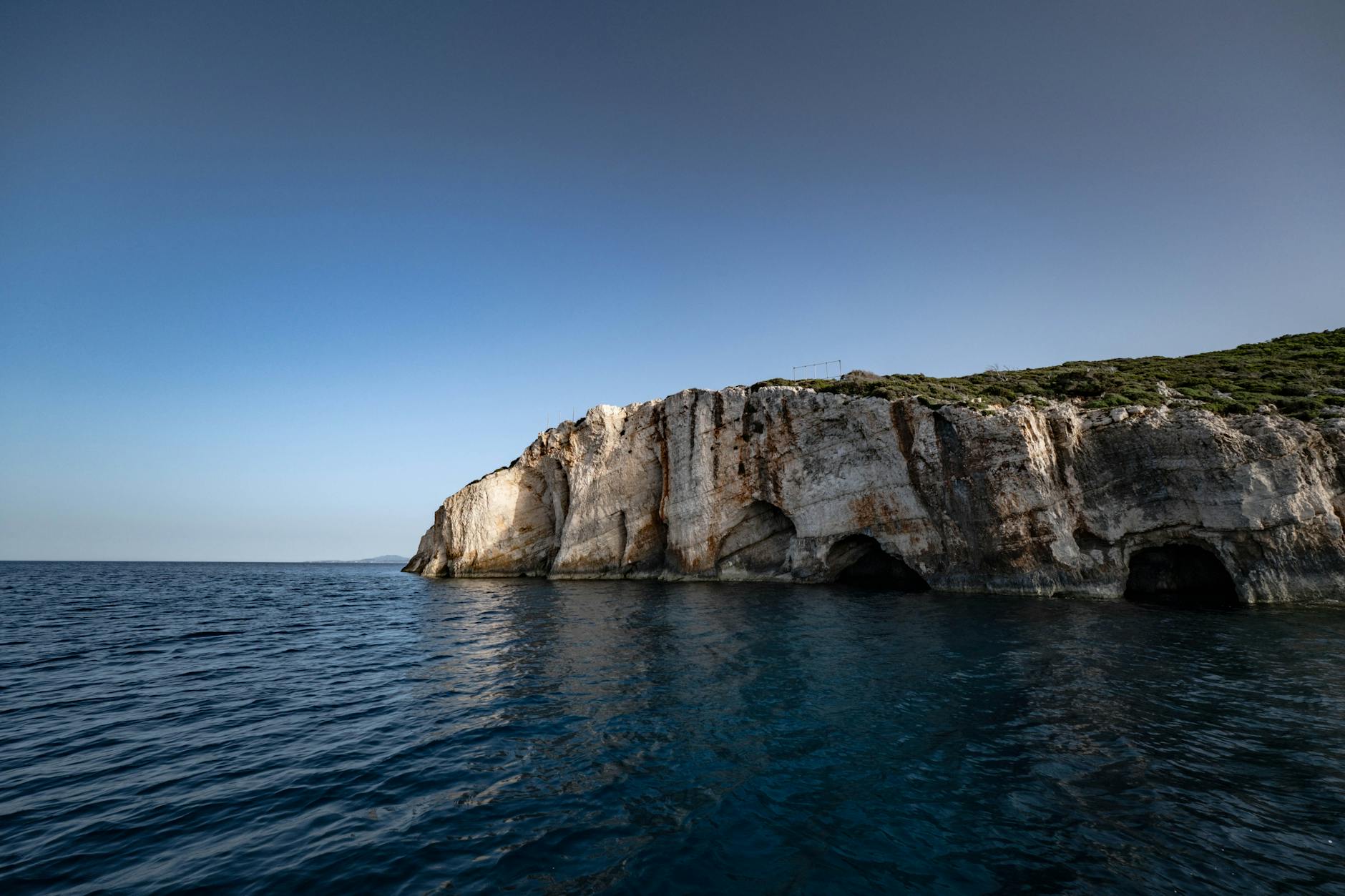 Rocky coastal cliff with blue caves at Paxos