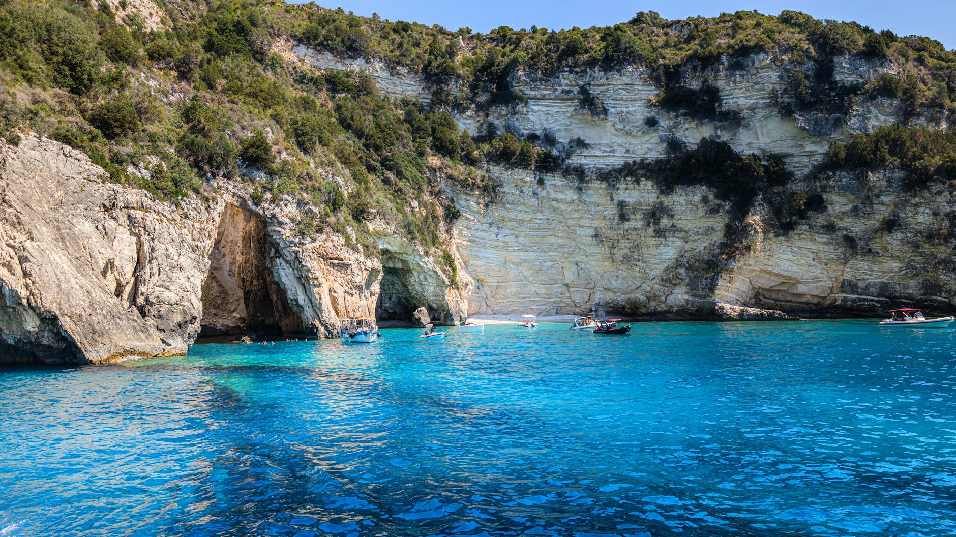 Rocky cliffs and boats on deep blue water
