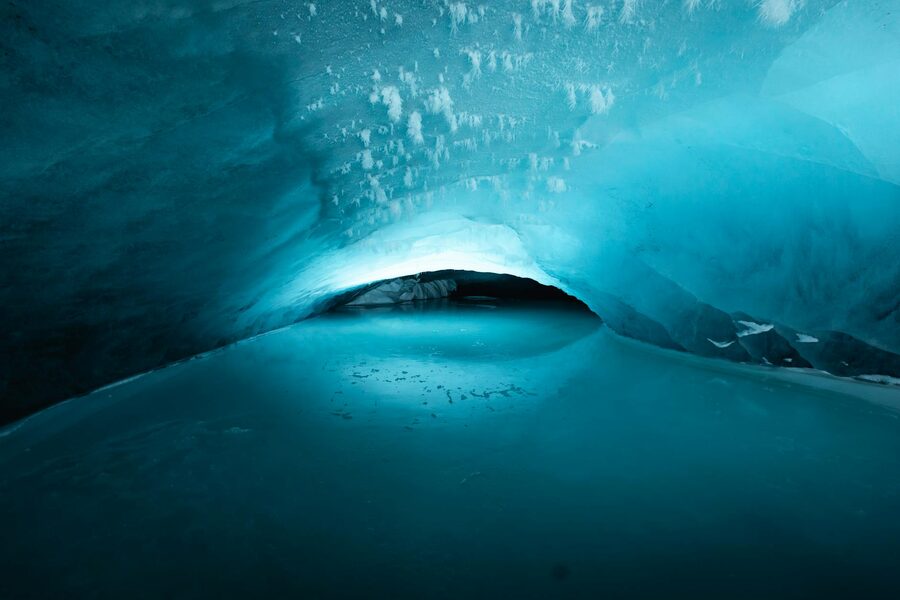 Natural blue light filtering through the entrance of a glacier cave
