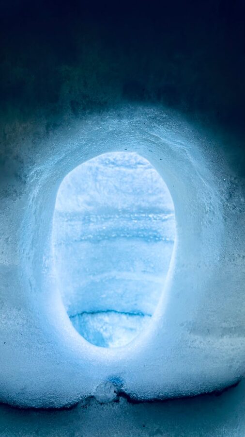 Glacier cave with dark volcanic ash streaks through the ice