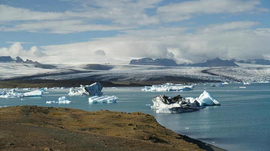 Vivid blue icebergs drifting in a glacial lake with mountains behind