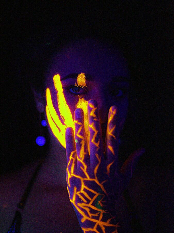 Hands glowing with UV fluorescent paint under black light