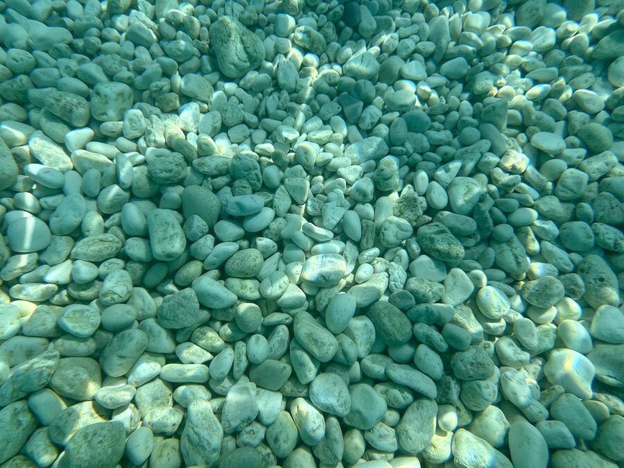 Smooth pebbles on clear water seabed