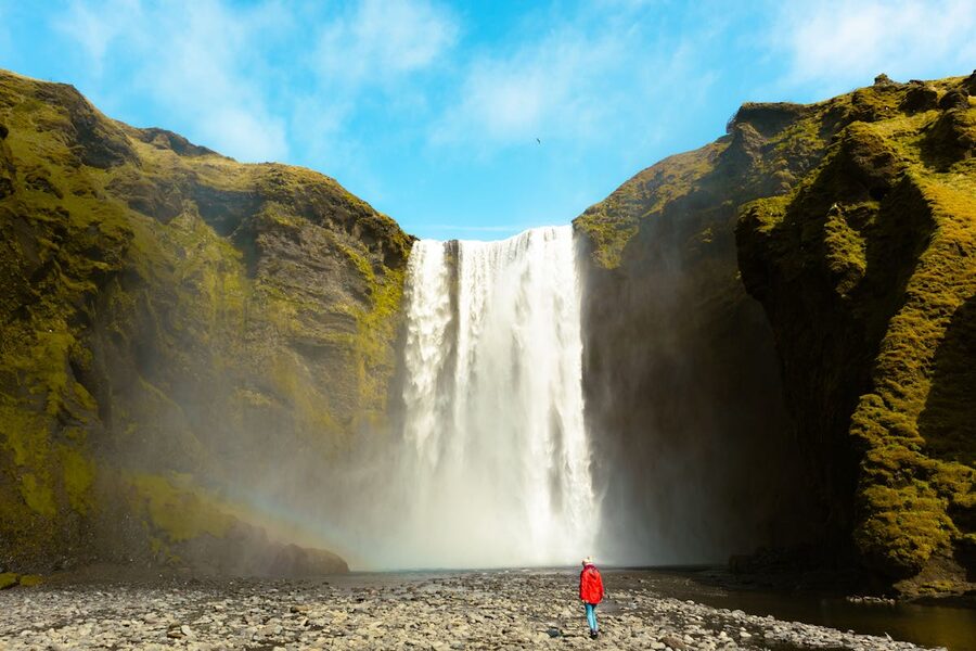 Skogafoss waterfall with person in red coat Iceland