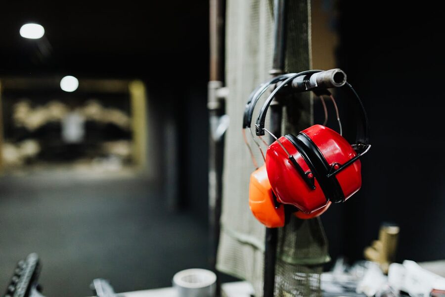 Red ear protection muffs hanging at shooting range station