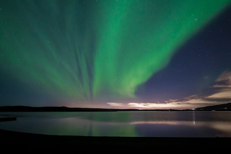 Aurora borealis reflecting over Icelandic lake at night