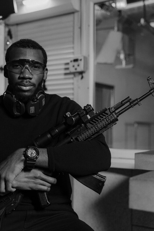 Man wearing ear and eye protection aiming rifle at indoor range