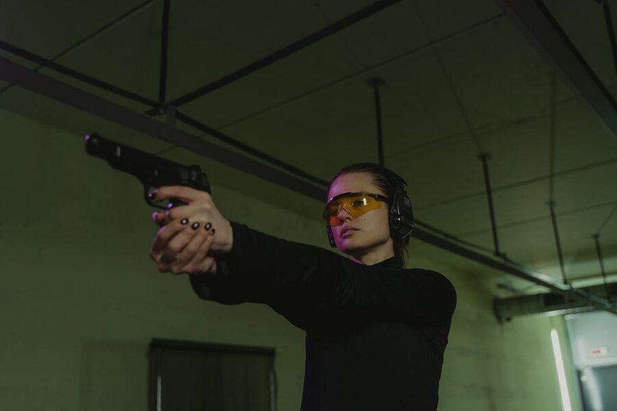 Woman aiming handgun with full safety gear at range