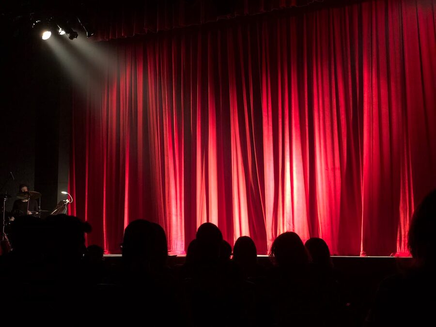 Theater audience viewing stage with red curtains